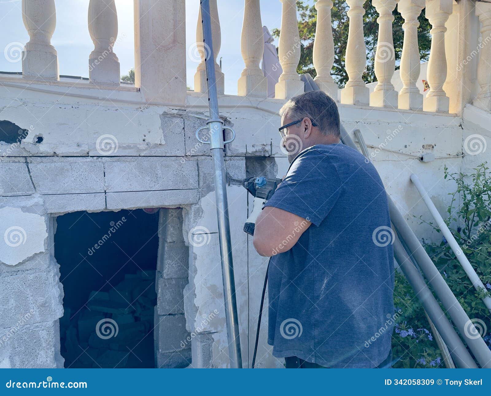 A Male Uses a Hammer Drill To Open a Hole in Block Work.Props Hold Up ...