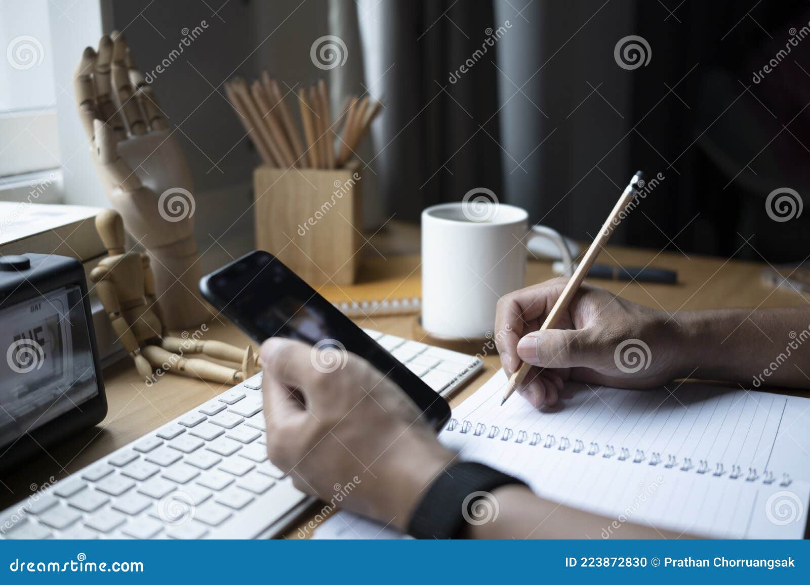 Male Using Mobile Phone and Making Note on Notebook. Stock Photo ...