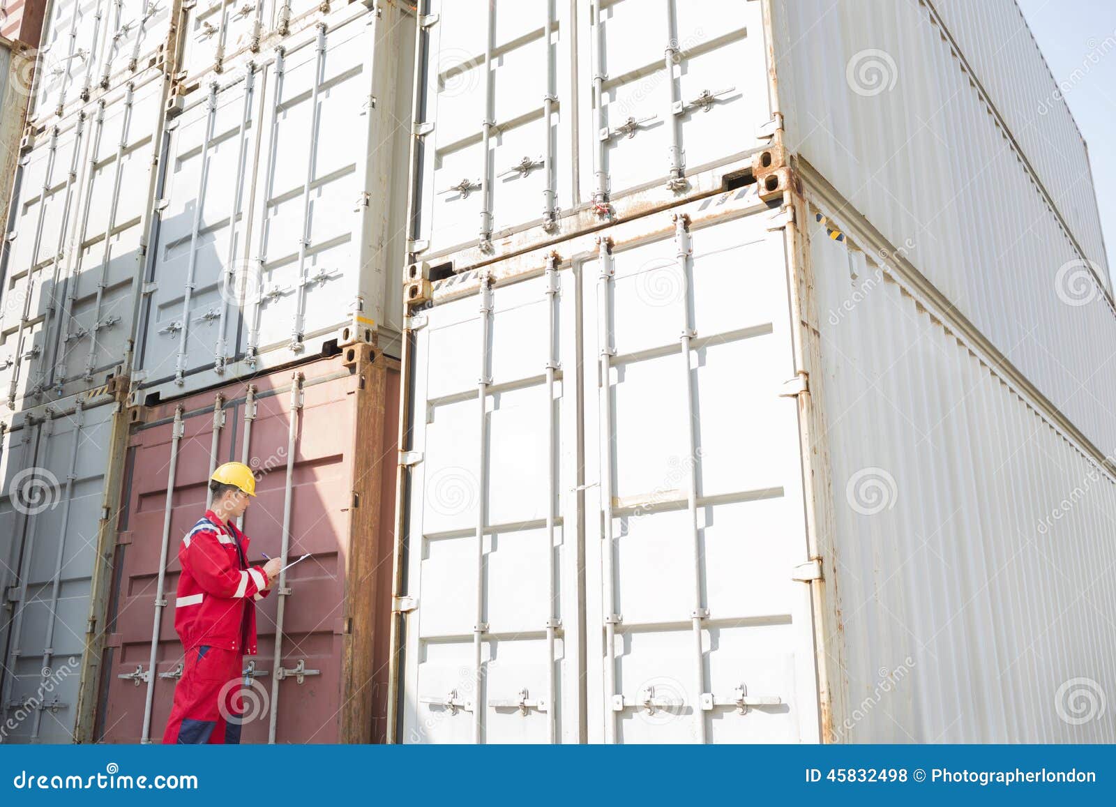 Male Worker Inspecting Cargo Containers while Writing on Clipboard in ...