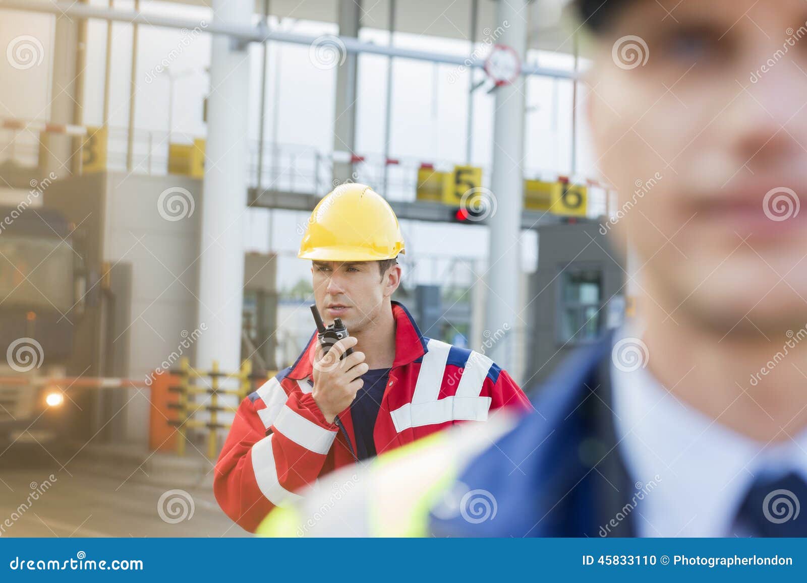 Male Worker Using Walkie-talkie with Colleague in Foreground at ...