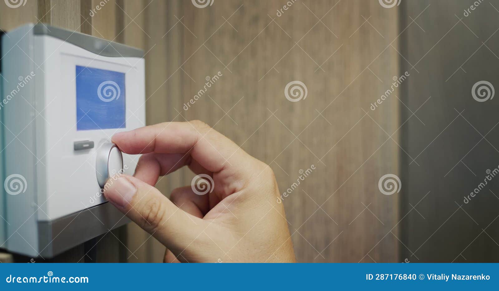 A Man Adjusts the Temperature in the House on a Wall-mounted Electronic ...