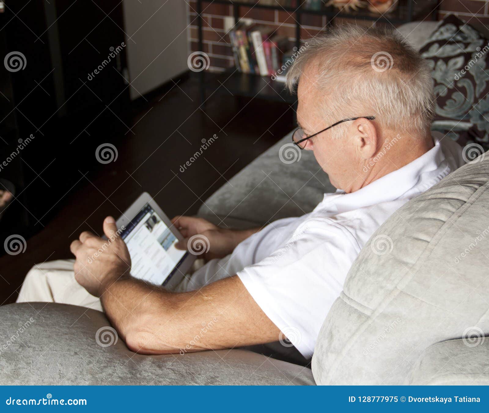 Man in Age Uses a Digital Gadget while Sitting on a Sofa in the ...