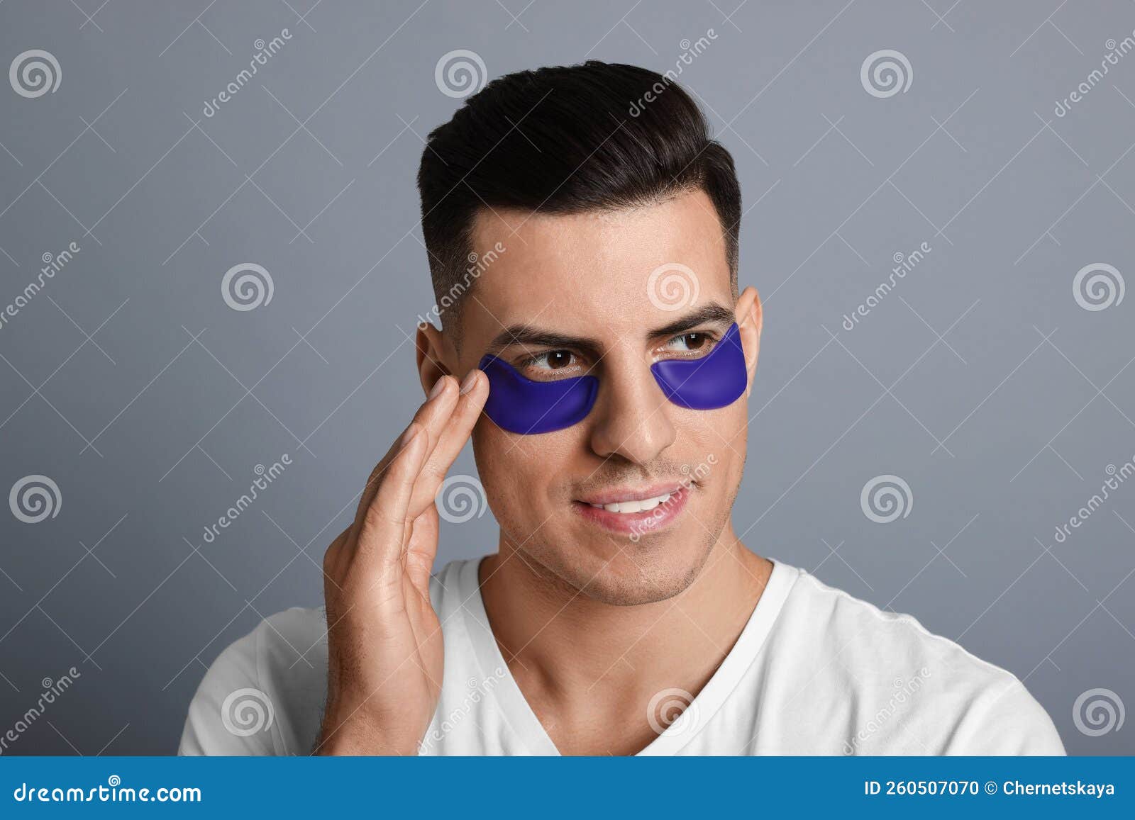 Man Applying Blue Under Eye Patch on Grey Background Stock Photo ...