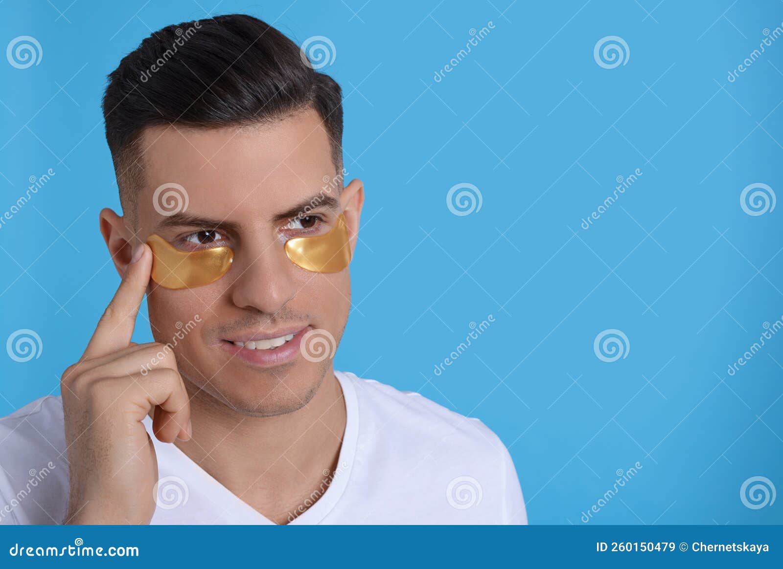 Man Applying Golden Under Eye Patch on Light Blue Background. Space for ...