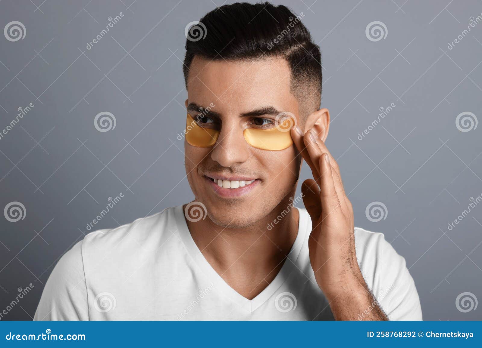 Man Applying Golden Under Eye Patch on Grey Background Stock Photo ...