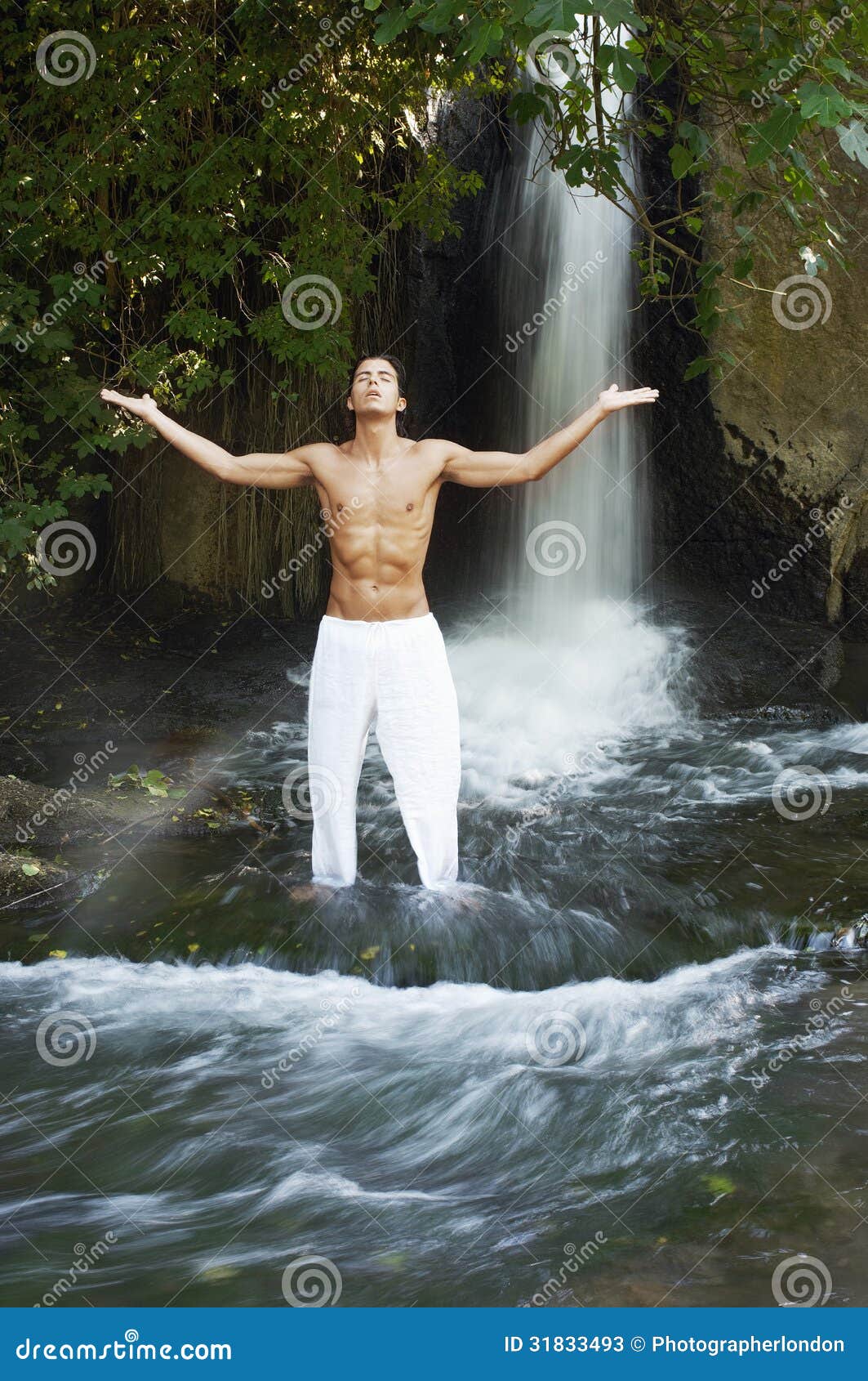 Man with Arms Outstretched Meditating Against Waterfall Stock Image ...