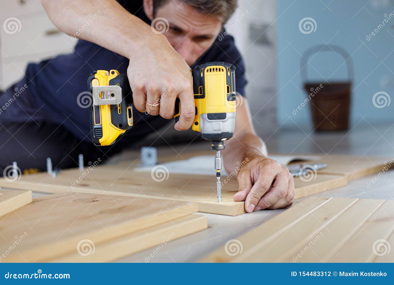 Man Assembling Furniture At Home Using A Cordless Screwdriver Stock