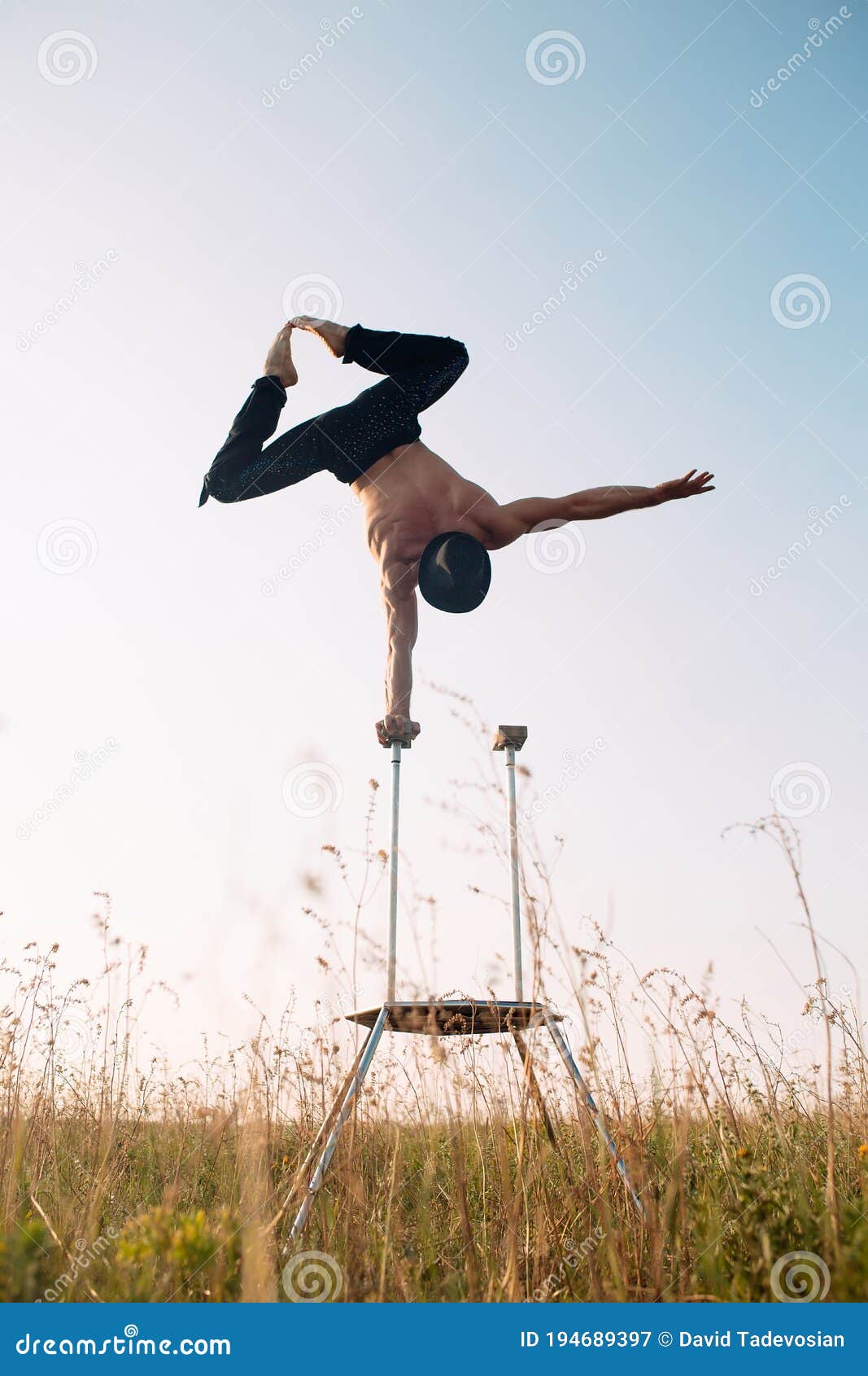 A Man of Athletic Build Performs Complex Gymnastic Exercises in a Field ...