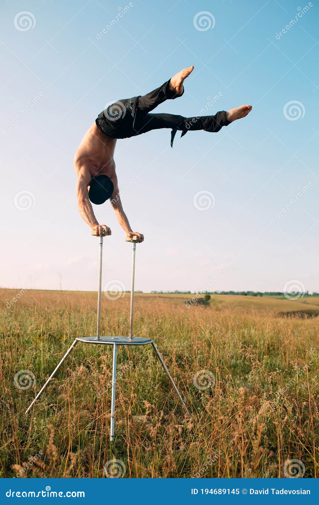 A Man of Athletic Build Performs Complex Gymnastic Exercises in a Field ...