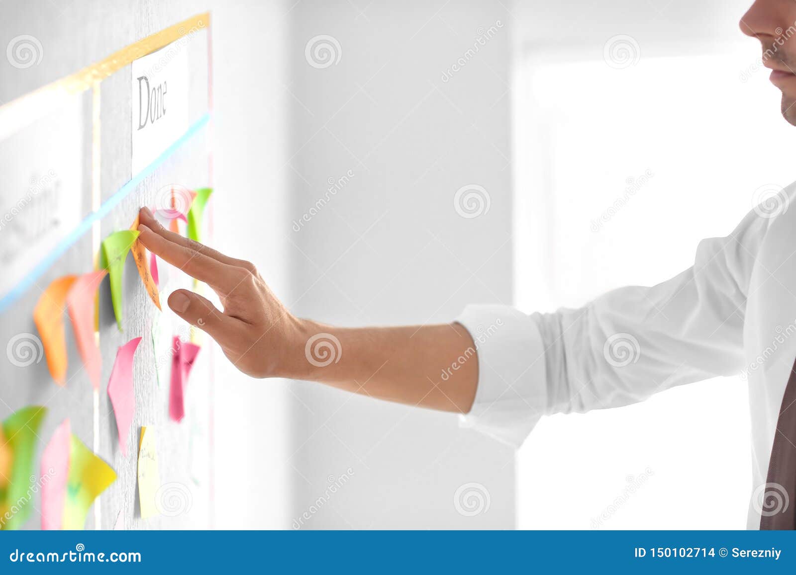 Man Attaching Sticky Note To Scrum Task Board in Office Stock Photo ...