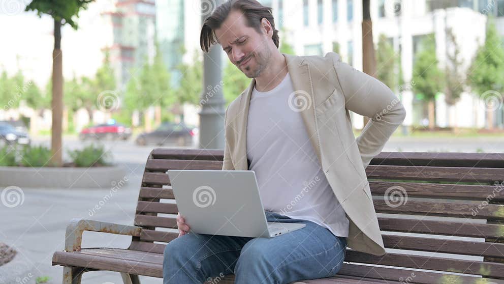Young Man with Back Pain Using Laptop while Sitting on Bench Stock ...