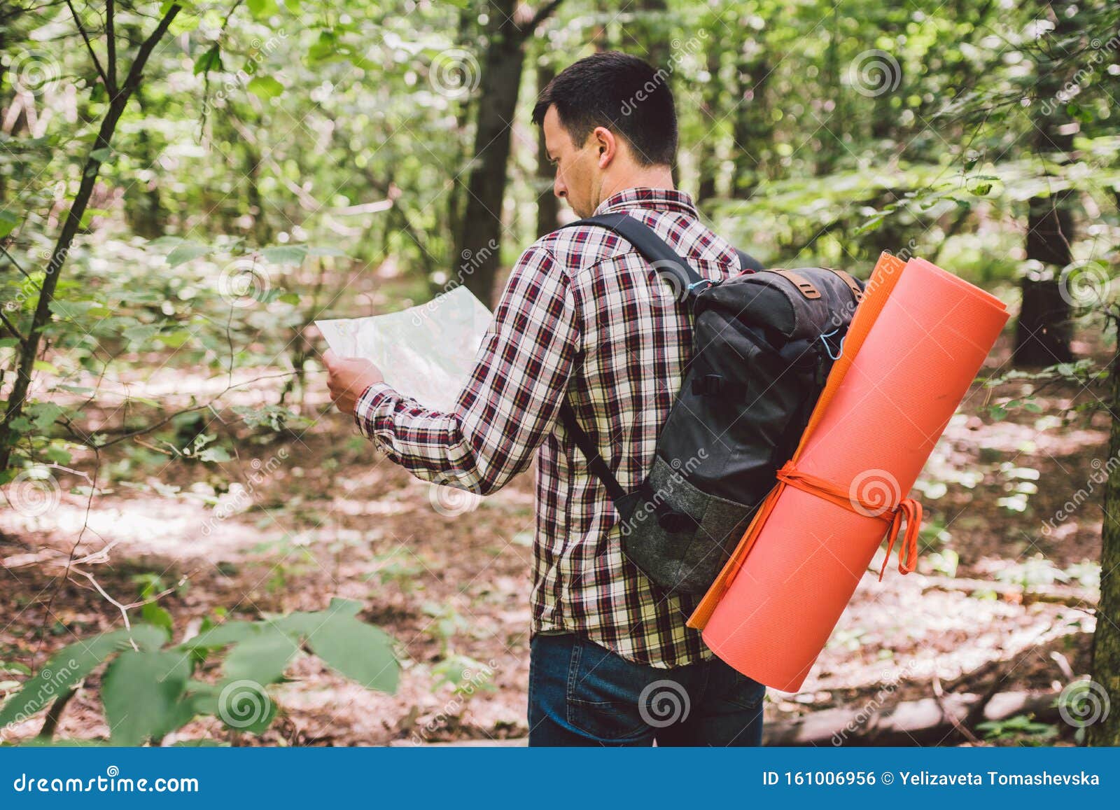 Man with Backpack and Map Searching Directions in Wilderness Area ...