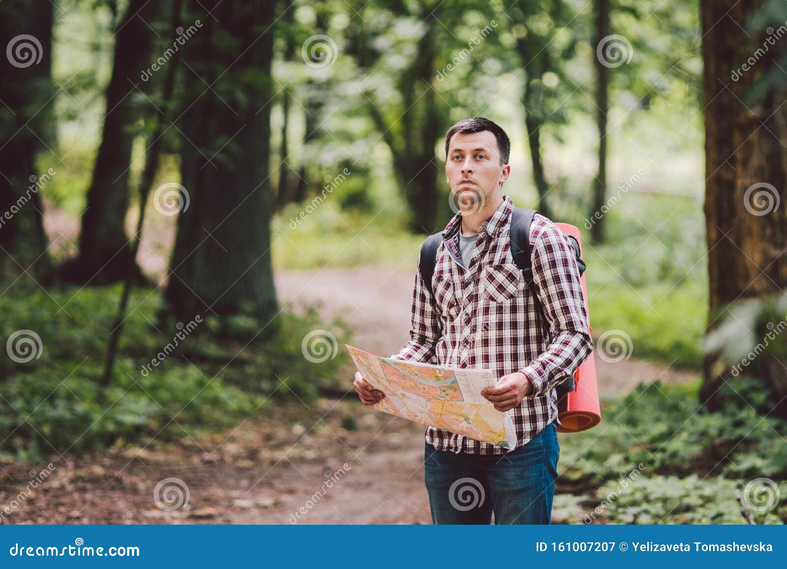 Man with Backpack and Map Searching Directions in Wilderness Area ...