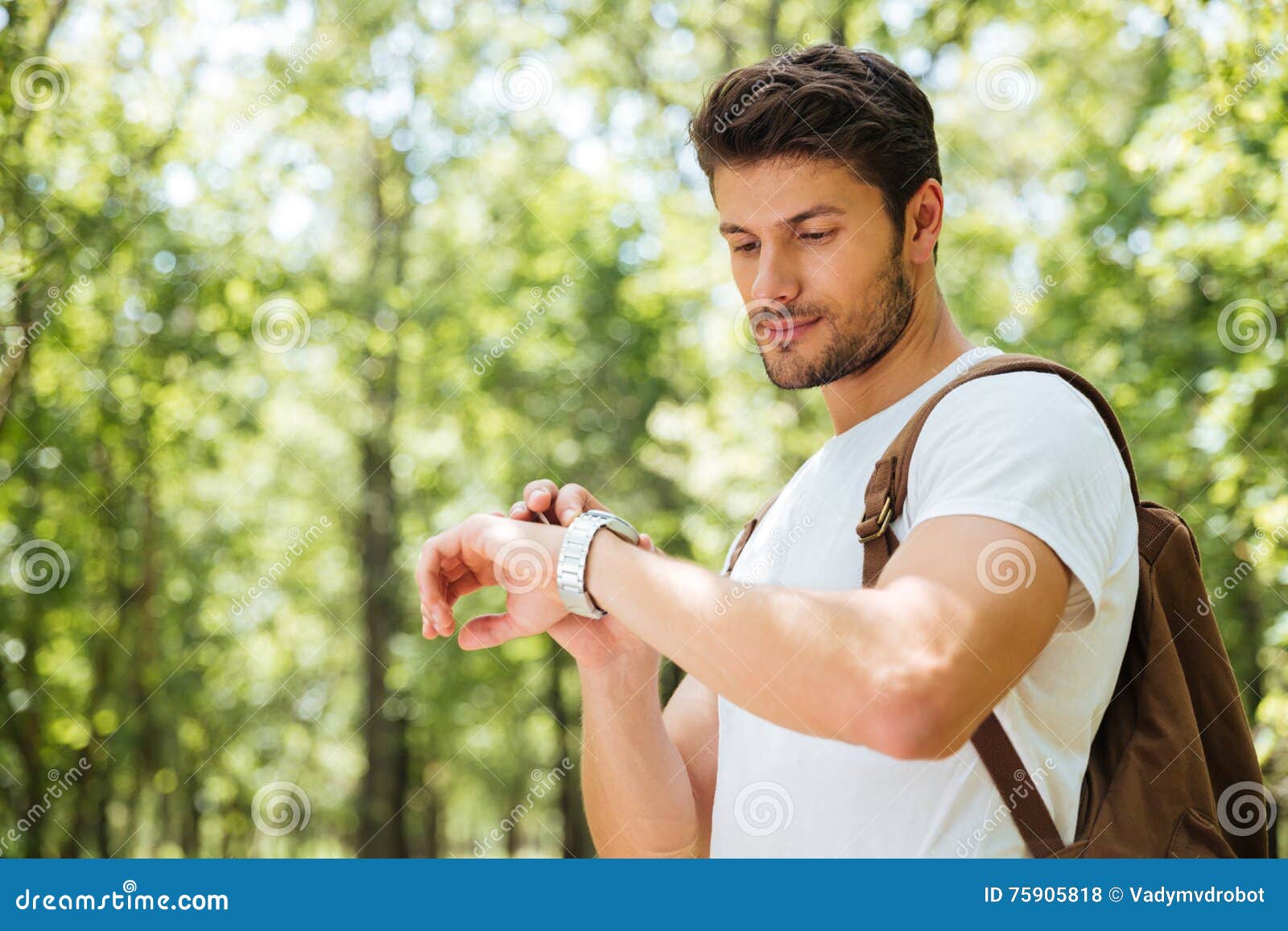 Man with Backpack Standing and Looking at Watch Outdoors Stock Photo ...