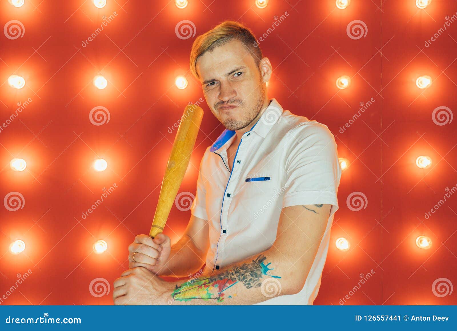 A Man with a Baseball Bat in His Hands Posing on a Red Background of ...