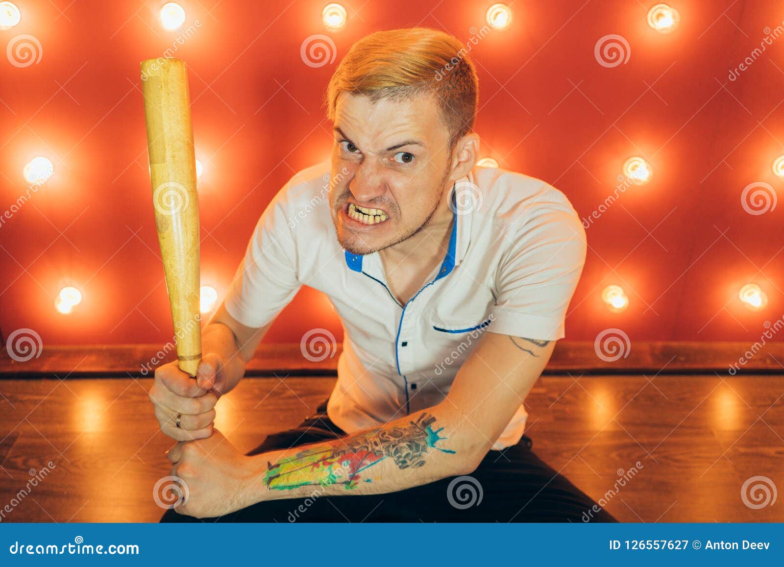 A Man with a Baseball Bat in His Hands Posing on a Red Background of ...