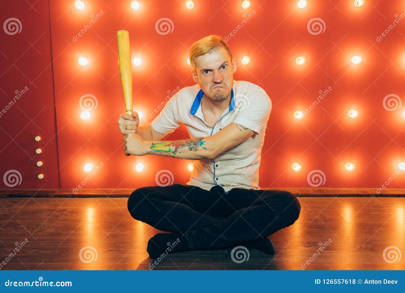 A Man with a Baseball Bat in His Hands Posing on a Red Background of ...