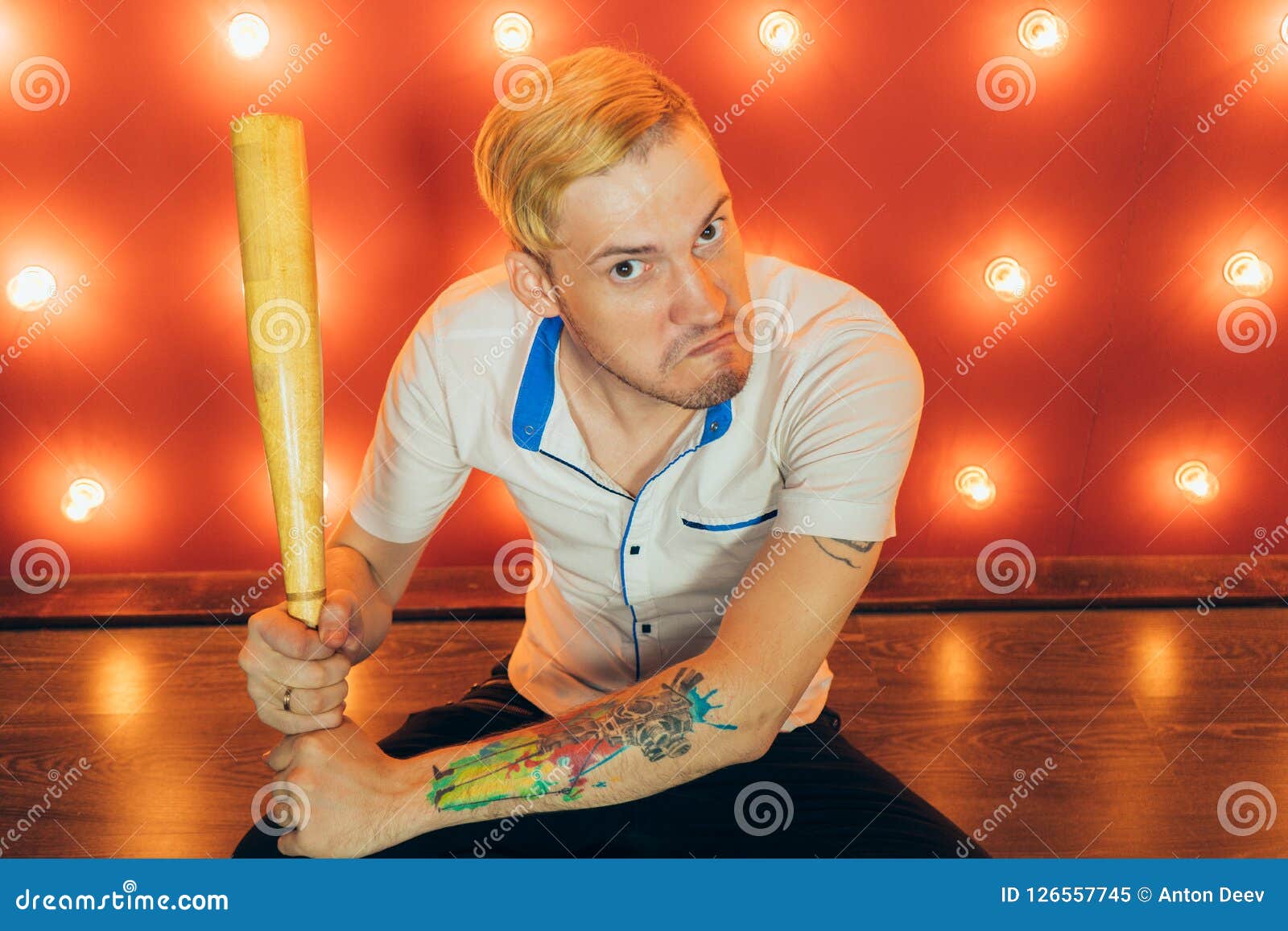 A Man with a Baseball Bat in His Hands Posing on a Red Background of ...