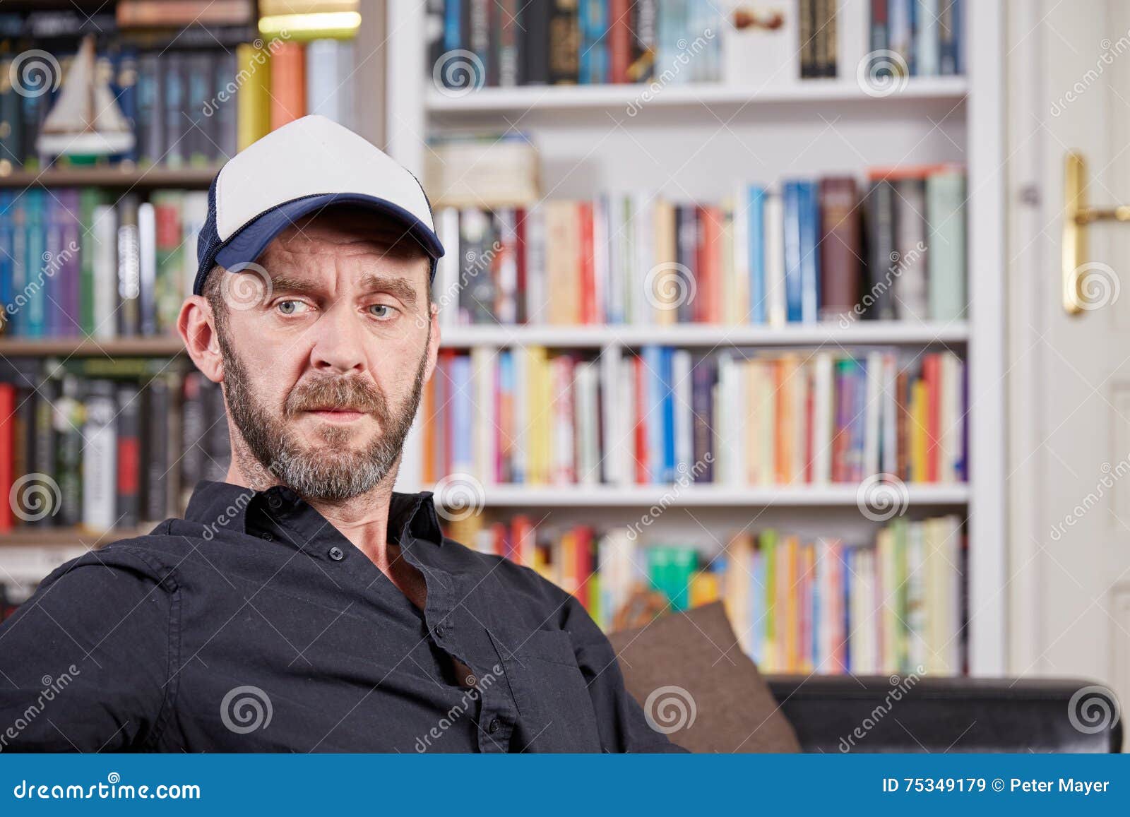 Man with Beard and Baseball Cap Sitting in a Library Stock Image ...