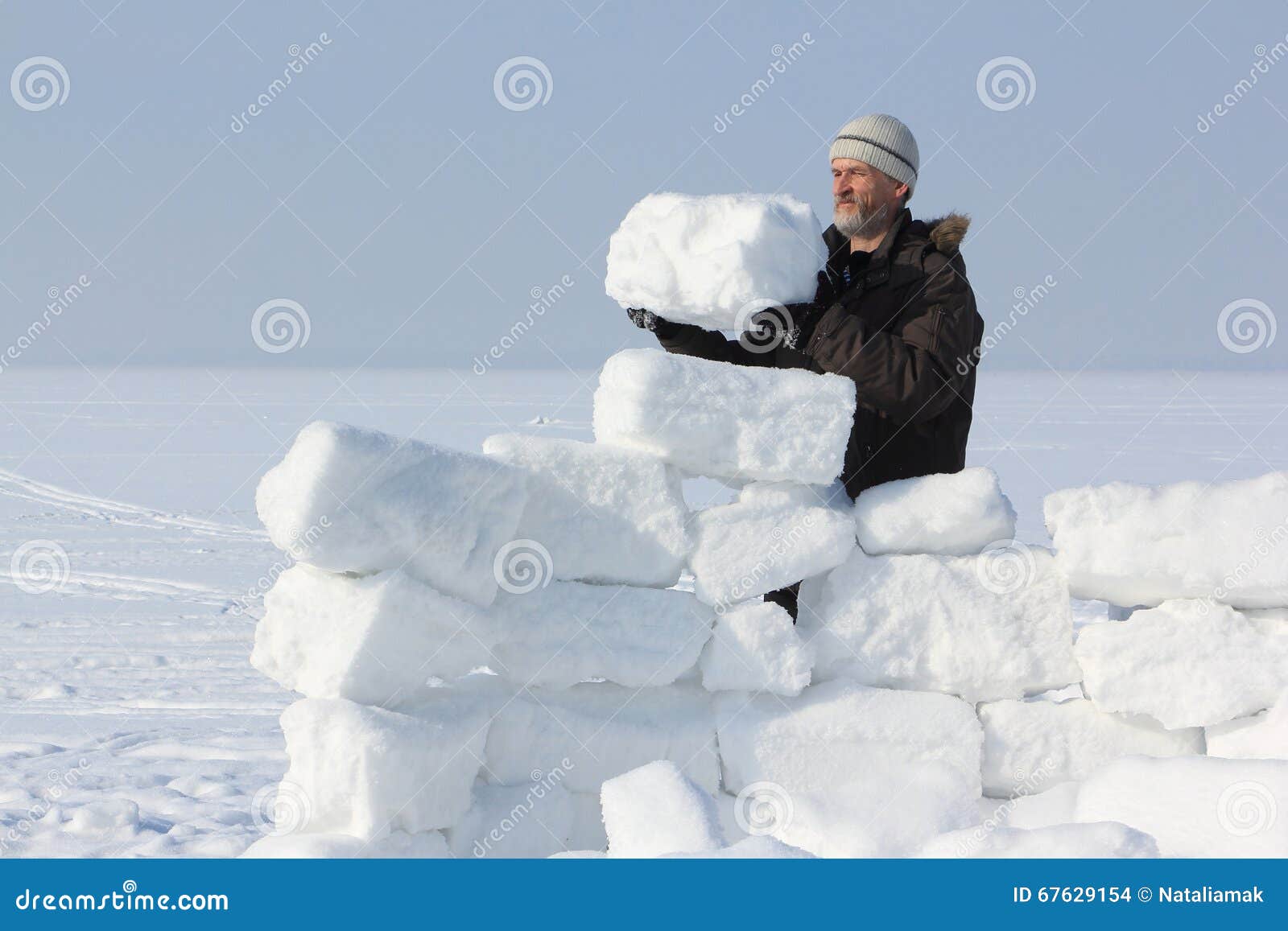 The Man with a Beard in a Gray Cap Building an Igloo Stock Photo ...