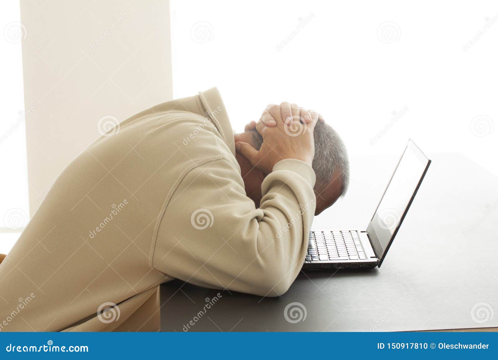 A Man Bends His Head Over a Computer in Despair while he Puts His Hands ...