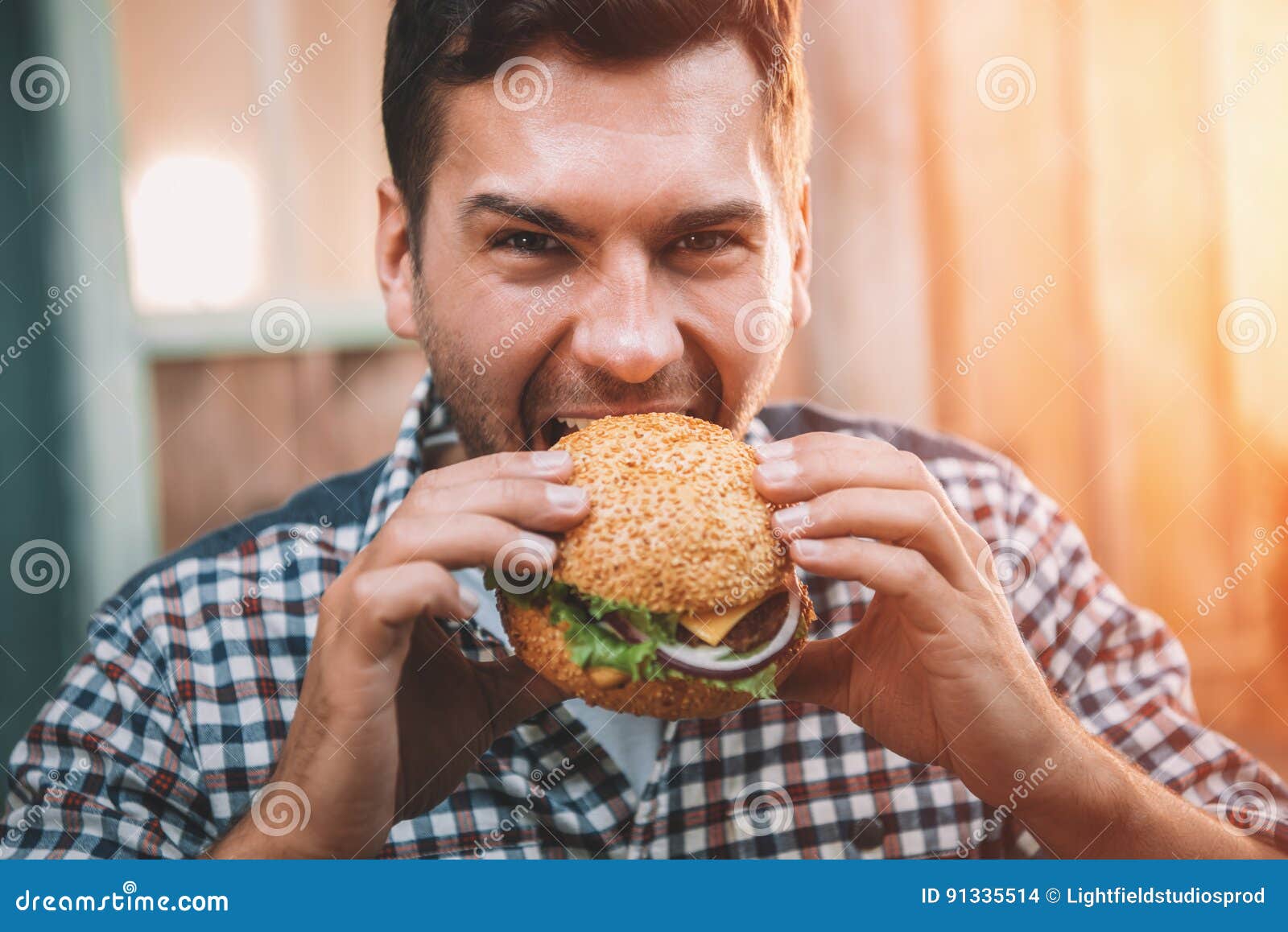 Man Biting Fresh Tasty Hamburger and Looking at Camera Stock Photo ...