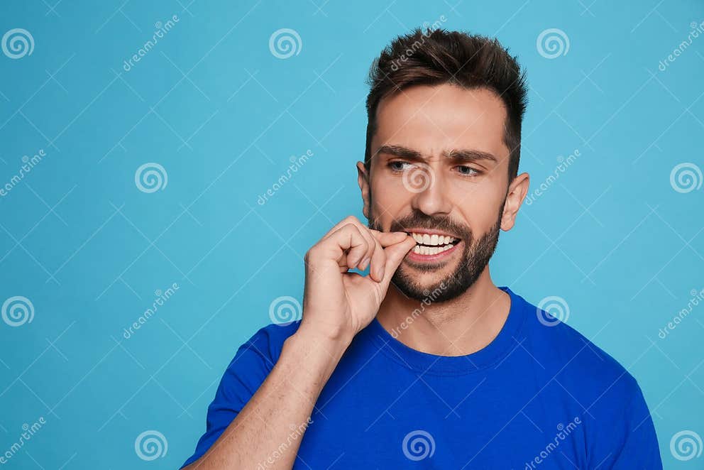 Man Biting His Nails on Light Blue Background. Space for Text Stock ...