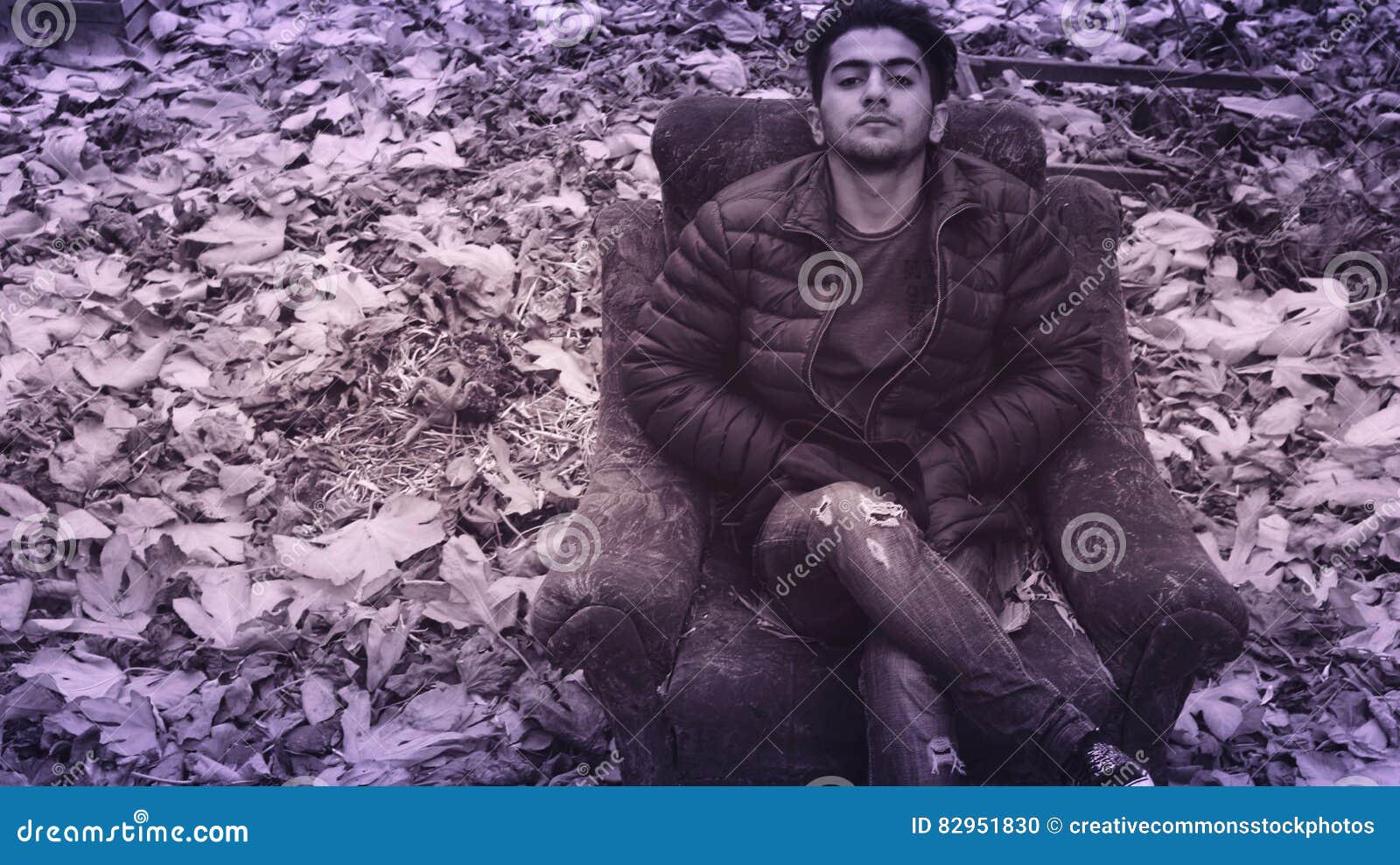 Man in Black Puffer Jacket and Distress Jeans Sitting in Couch Stock ...