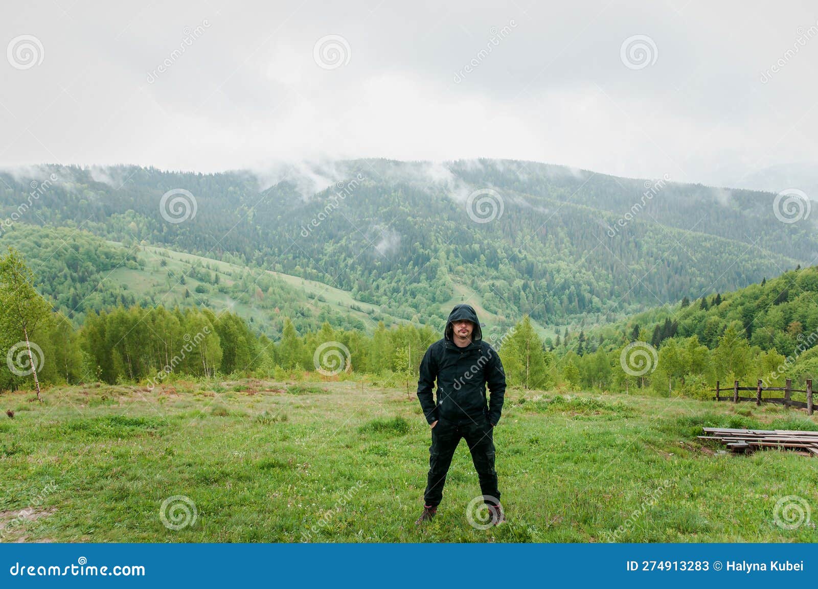 A Man in a Black Trekking Suit Against the Backdrop of Mountains Stock ...