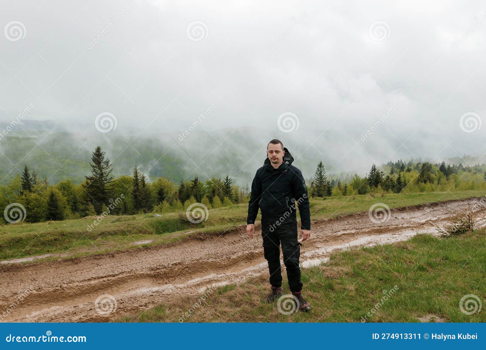 A Man in a Black Trekking Suit Against the Backdrop of Mountains Stock ...