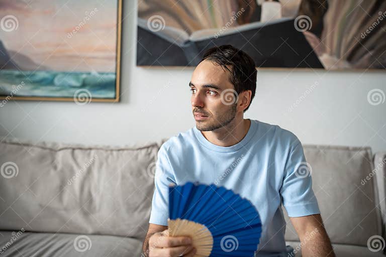 Man Blowing with Fan, Coping with Heat. Guy Experiencing Discomfort ... Man Blowing with Fan, Coping with Heat. Guy Experiencing Discomfort ...