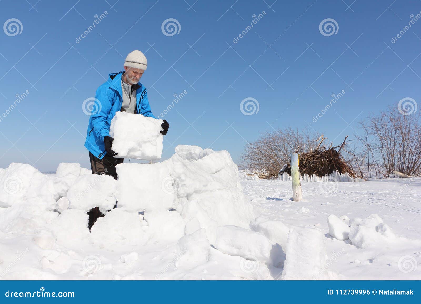 Man in a Blue Jacket Building an Igloo on a Glade Stock Photo - Image ...