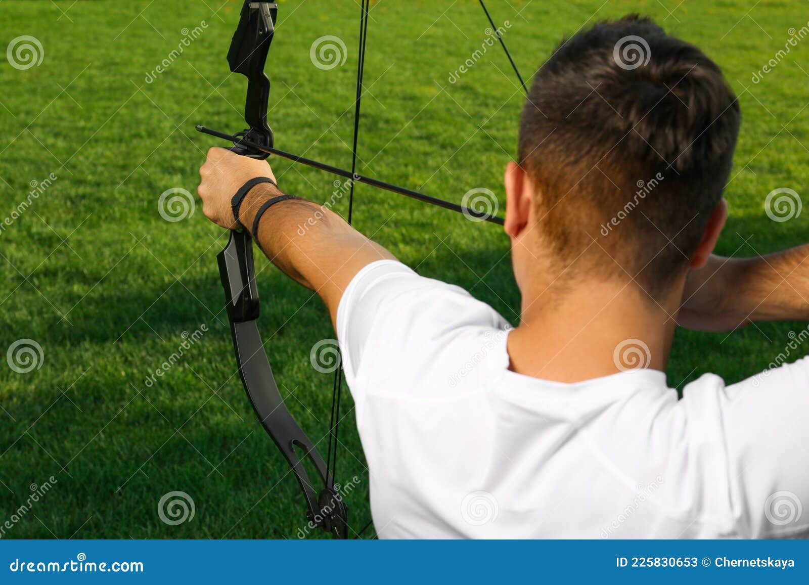 Man with Bow and Arrow Practicing Archery on Grass, Back View Stock ...