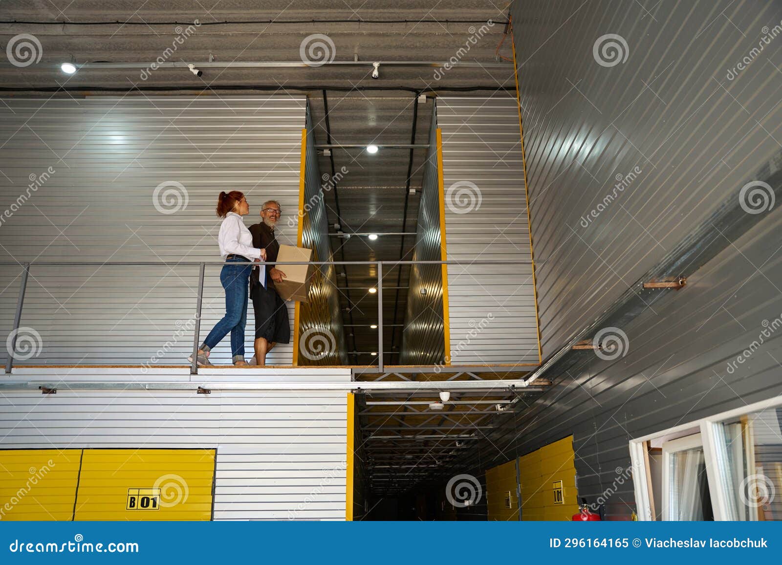 Man with a Box and a Woman Walk through Warehouse Stock Image - Image ...