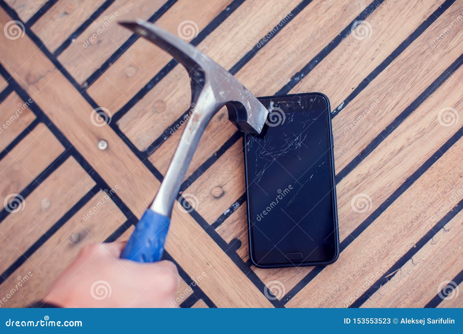 A Man is Breaking a Smartphone Lying on a Wooden Table with a Hammer ...