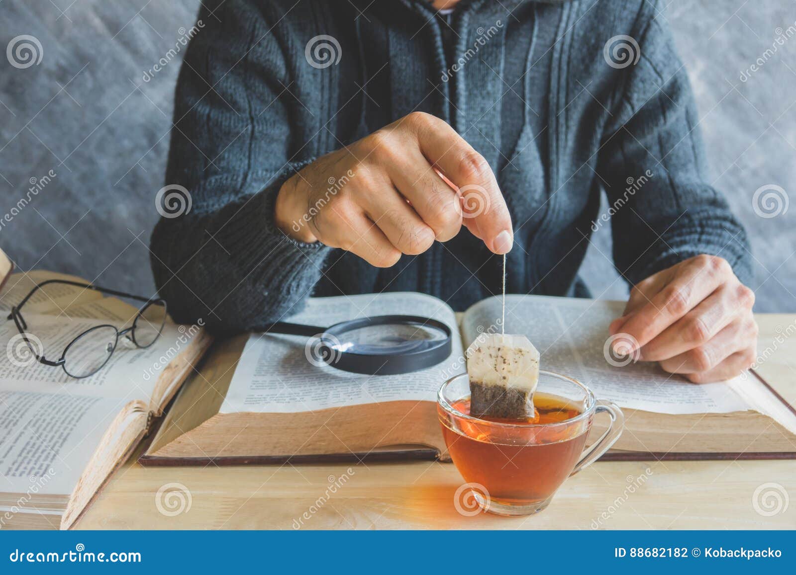 A Man Brewing Tea Bag with Glass of Tea on Table in Reading Tim Stock ...