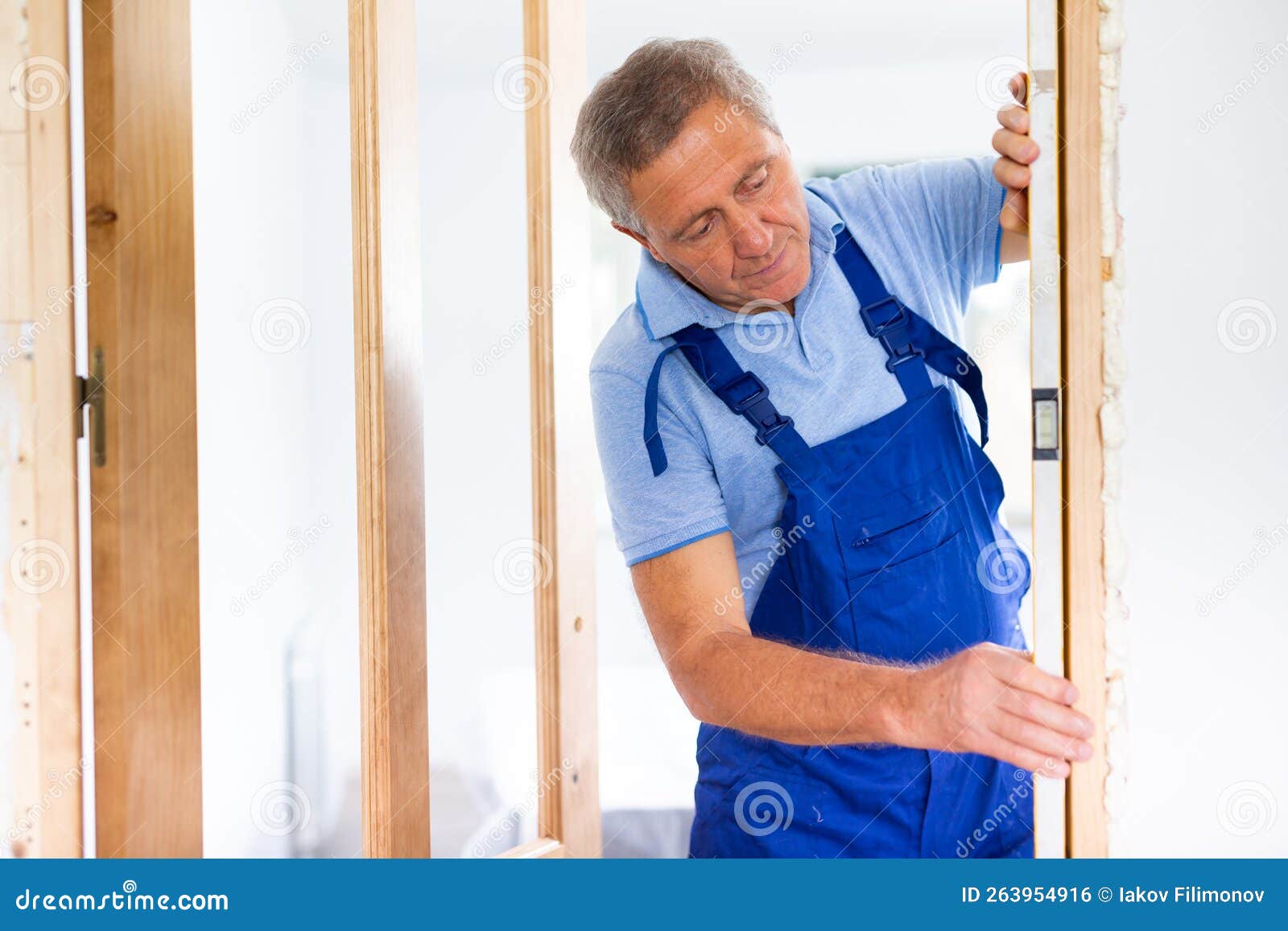 Man Builder in Blue Overalls Measures Deviations from a Given Vertical ...