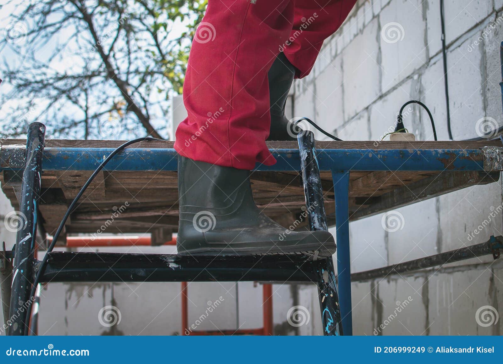 A Man the Builder Goes Down the Scaffolding. in the Frame There are ...