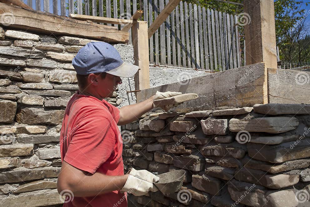 Man building stone wall stock photo. Image of build - 157004182