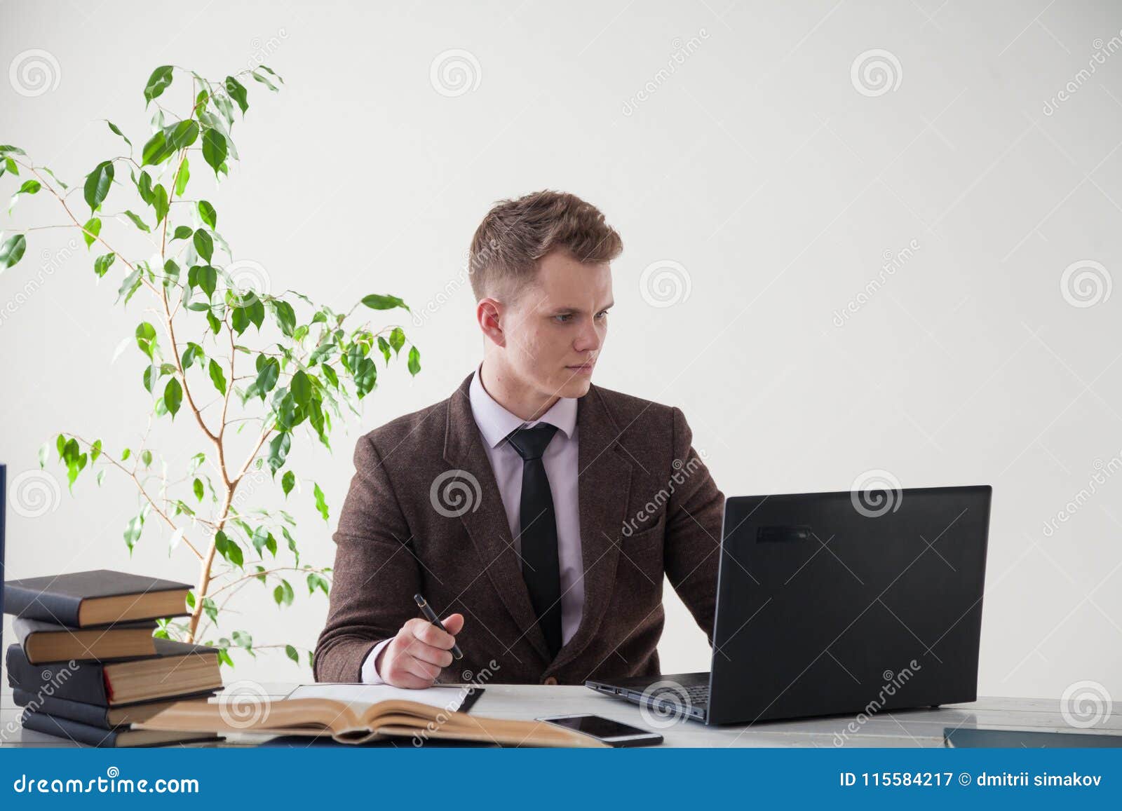 A Man in a Business Suit Works at a Desk with a Computer and Books in ...