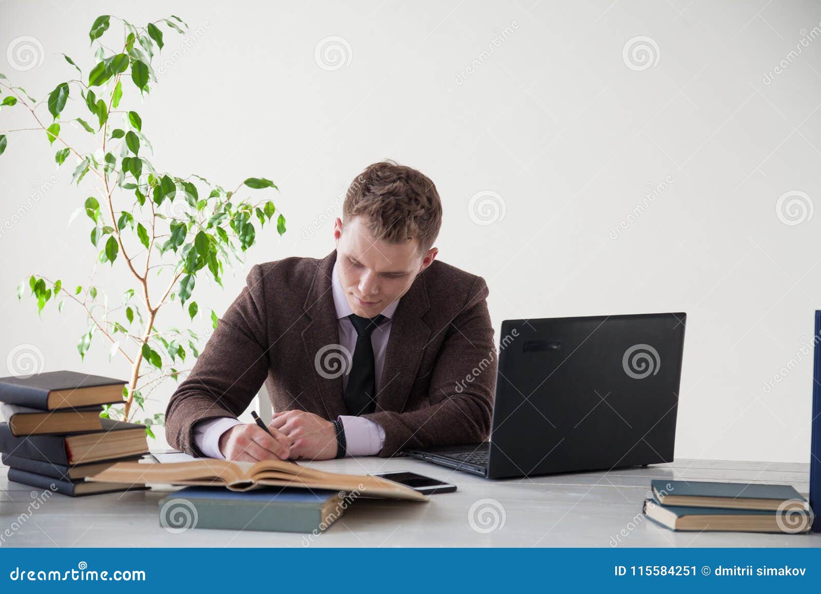 A Man in a Business Suit Works at a Desk with a Computer and Books in ...