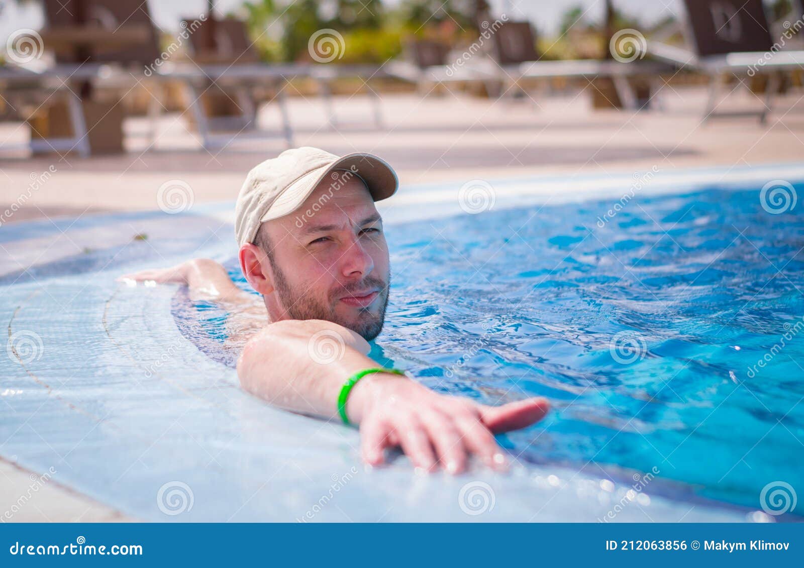 A Man in a Cap is Resting in the Pool. Portrait of a Guy in the Pool of ...
