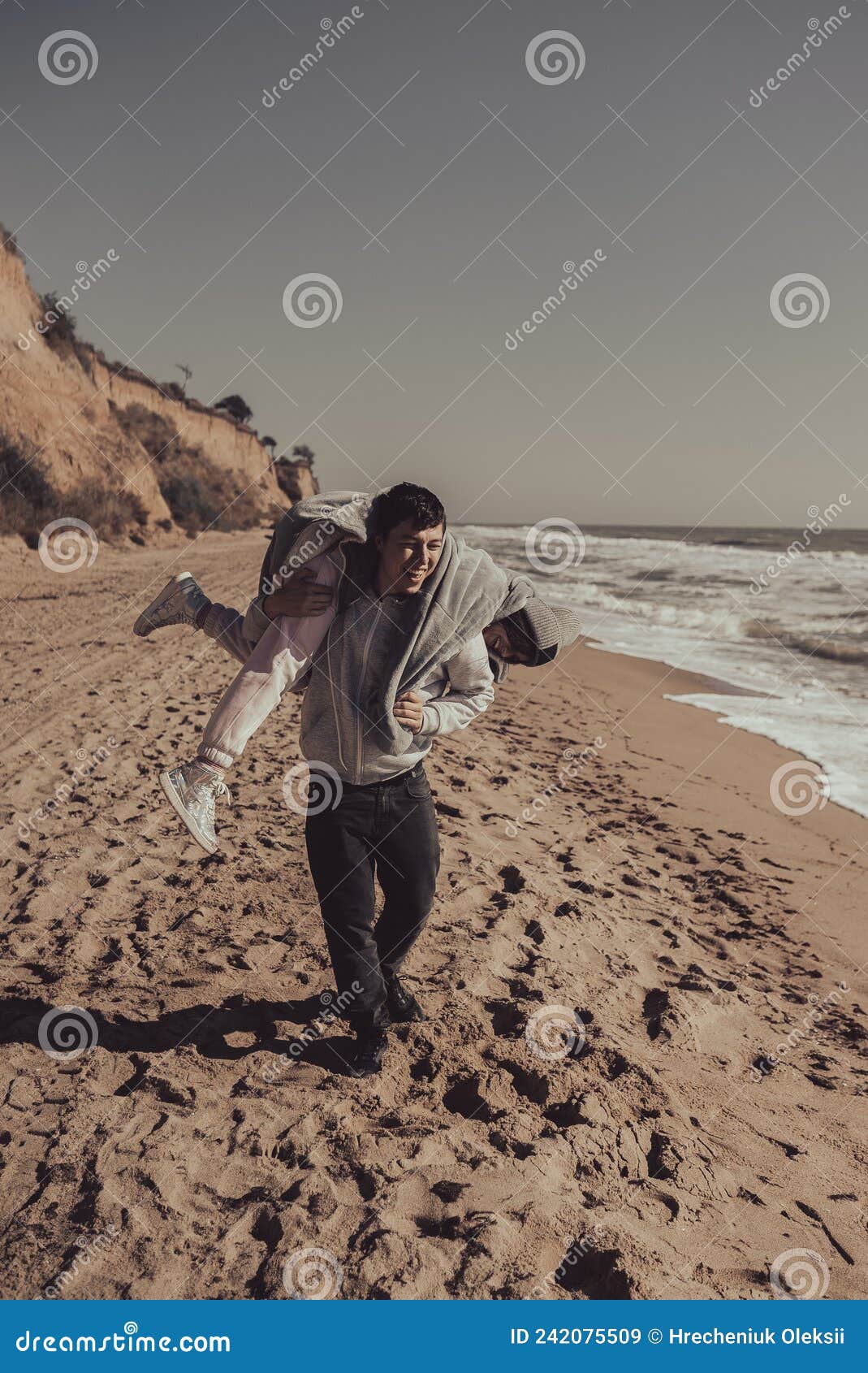 Man Carries His Girlfriend On Back Couple Having Fun On The Seashore