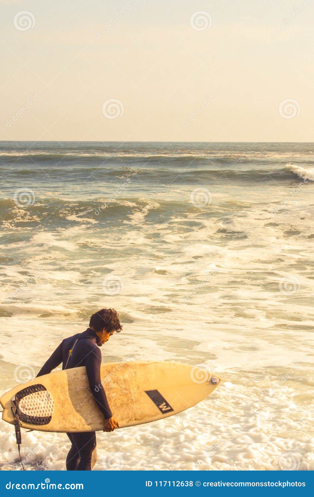 Man Carrying Surfboard Near Shoreline Picture. Image: 117112638