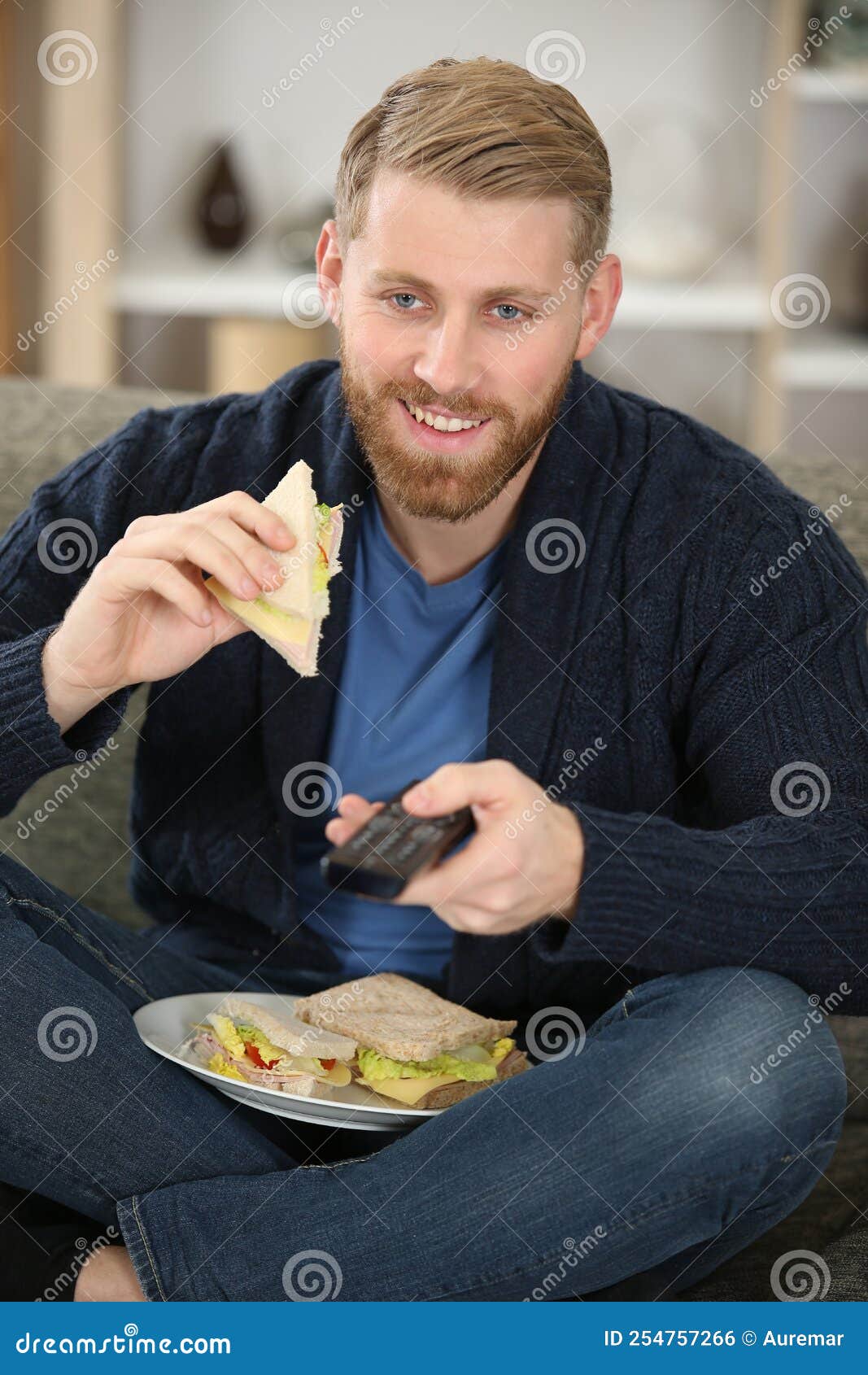 Man Changing Tv Channel with Remote Control while Eating Sandwich Stock ...