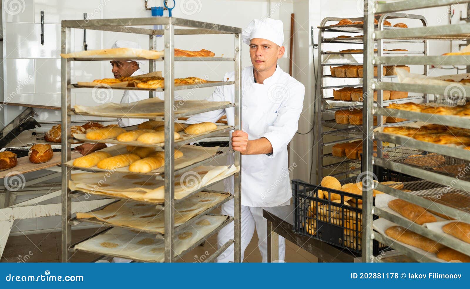 Man in Chefs Uniform Rolling Trolley with Bread in Bakery Stock Photo ...