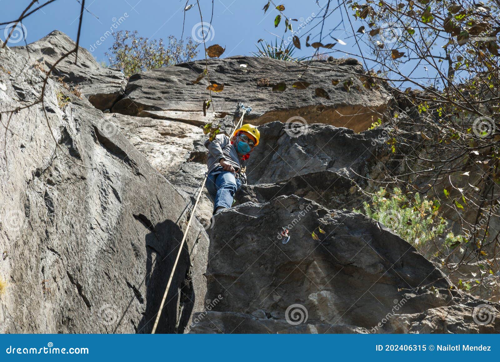 Man Climbs on a Vertical Rock Wall on the Blue Sky Background Stock ...