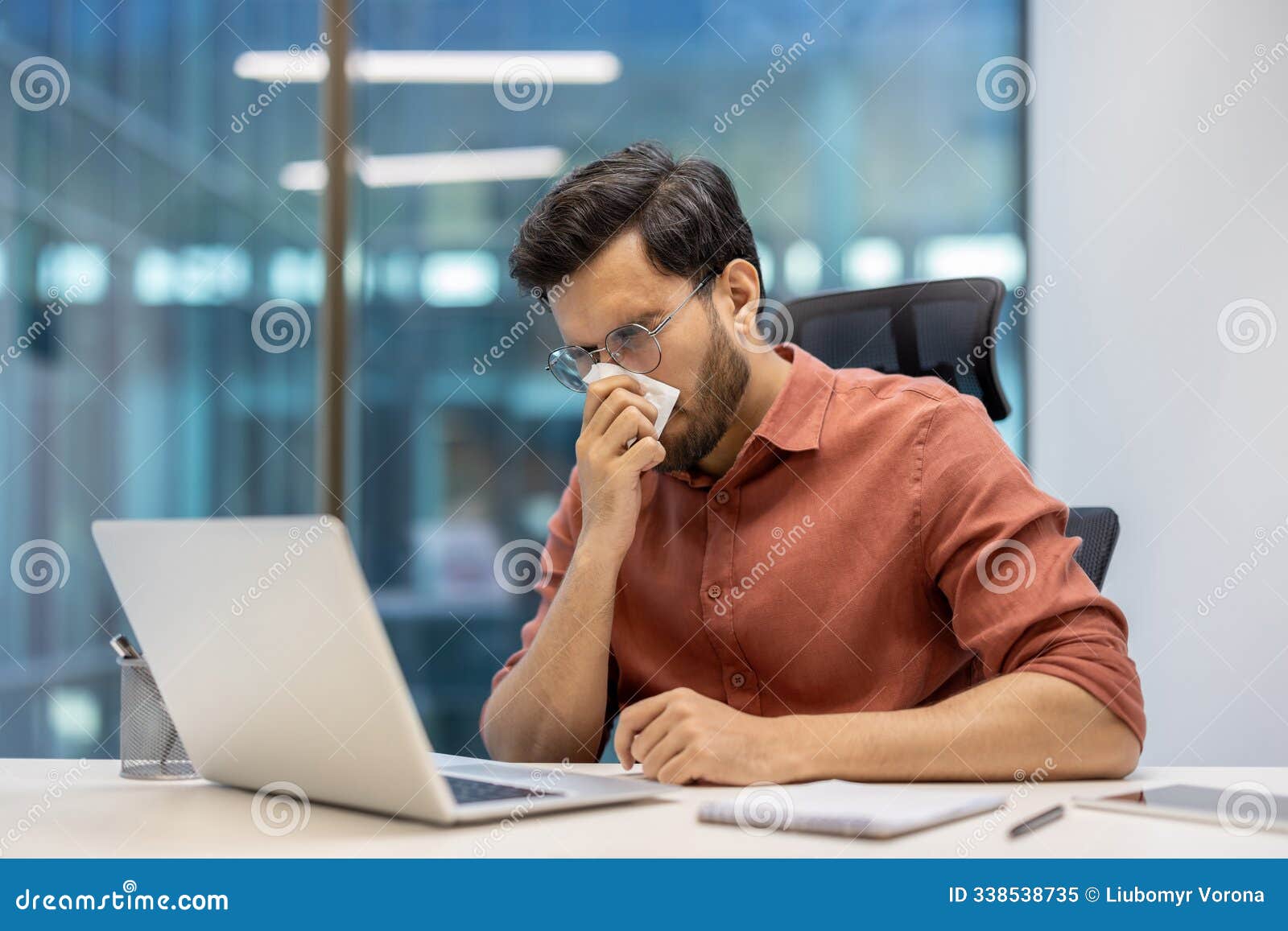 Man with Cold at Office Using Tissue while Working on Laptop in Modern ...