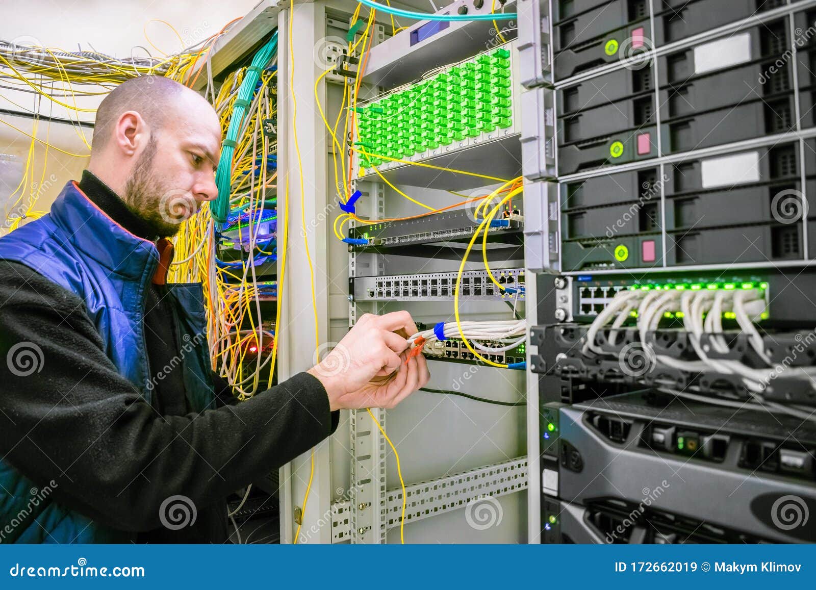 A Man Commutes Internet Wires In A Server Rack. The System ...