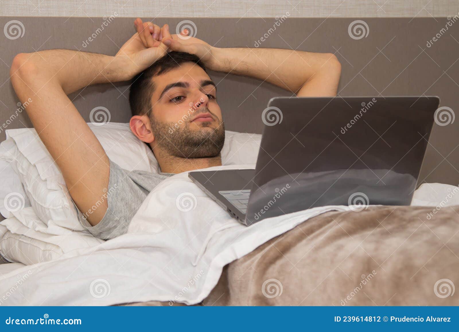 Man with computer in bed stock photo. Image of male - 239614812